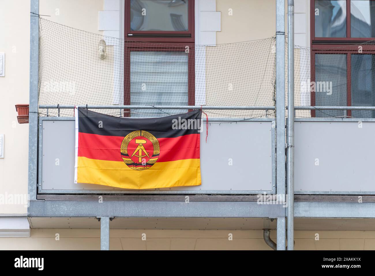 A flag of the GDR hanging on a balcony of an apartment building ...