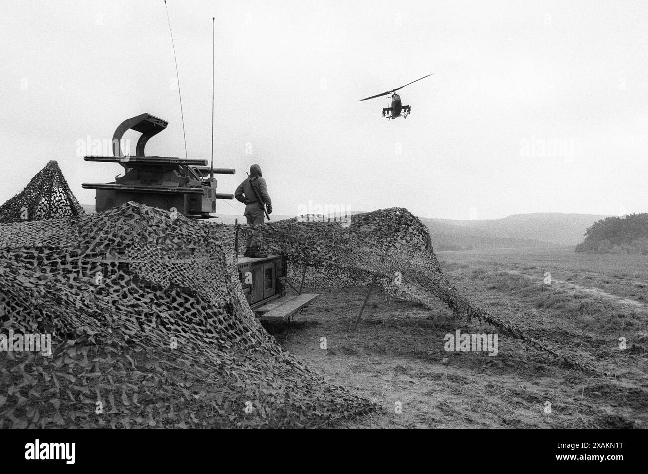 Combat helicopter flying low over camouflaged military equipment. US ...