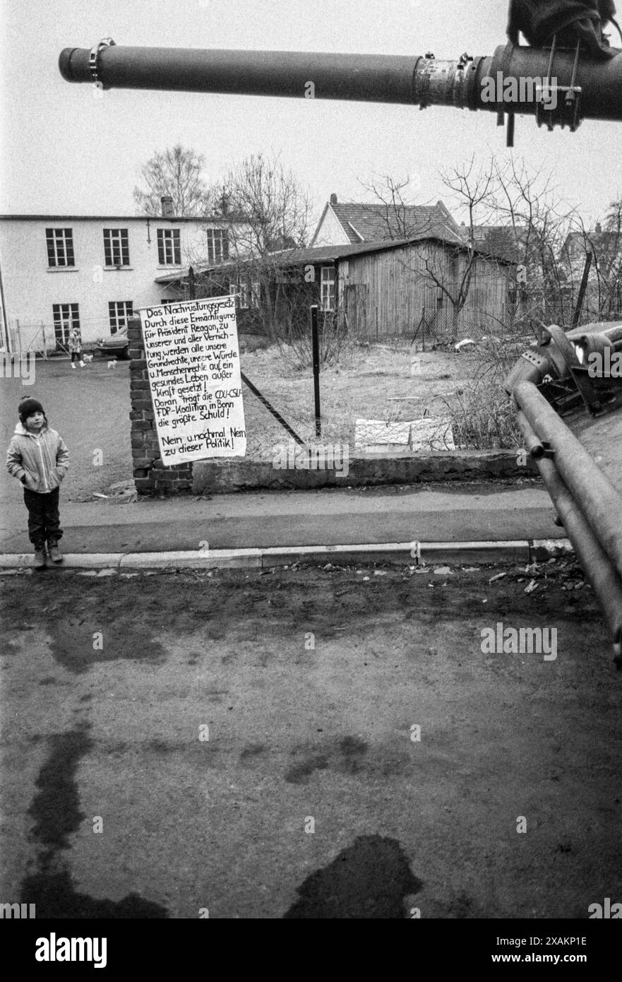 Child observes a passing column of tanks. Next to the child hangs a ...