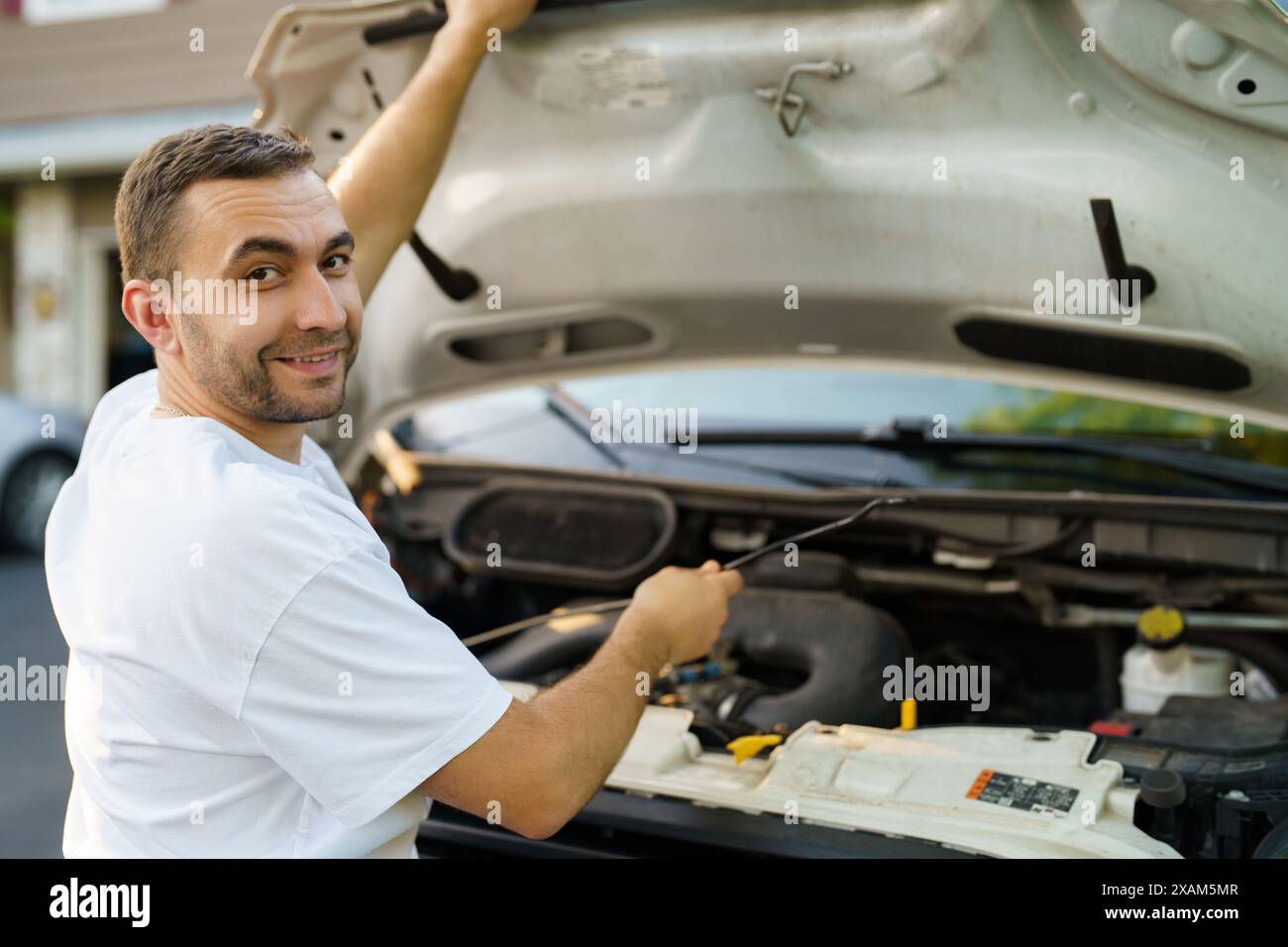 Portrait of young man looking under the hood of his car Stock Photo - Alamy