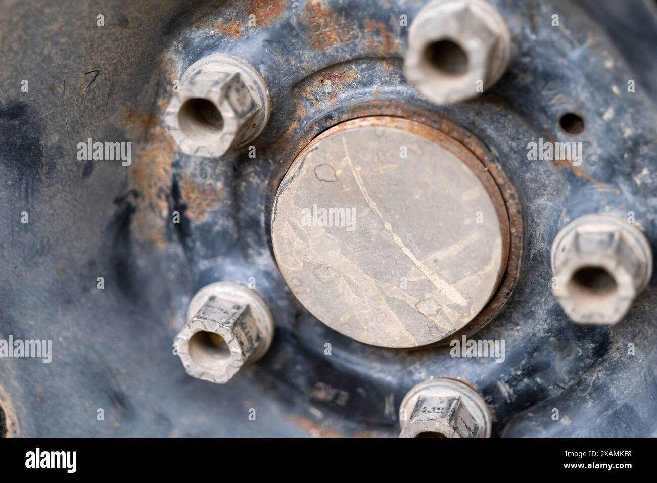 Explore the intricate textures of a rusty car tire bolt on a wheel hub ...