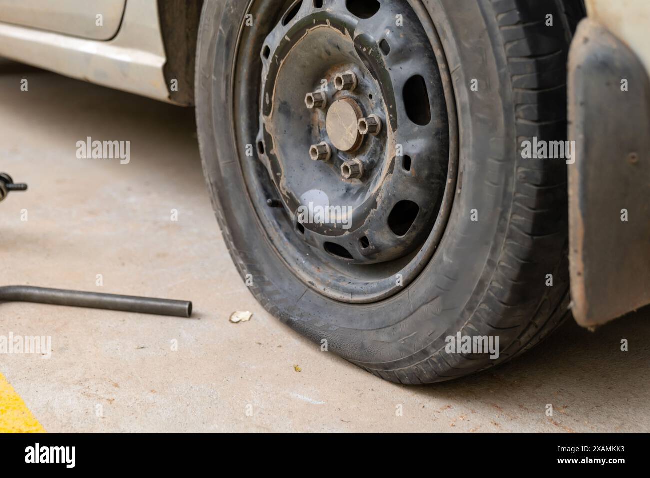 Close-up view of a deflated car tyre with visible tread patterns lying ...