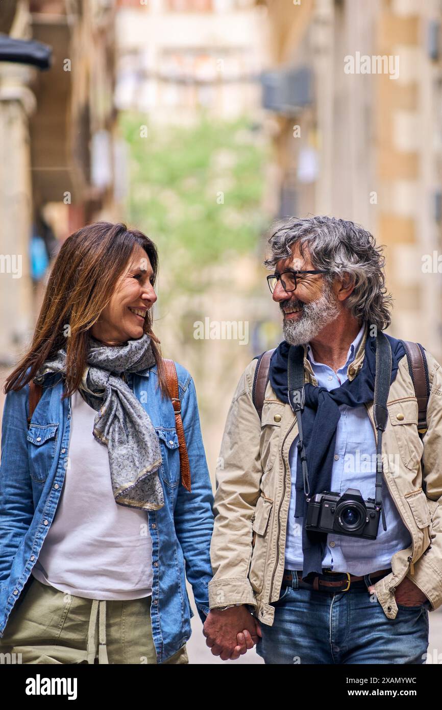 Happy mature romantic couple look at each other smiling holding hands ...