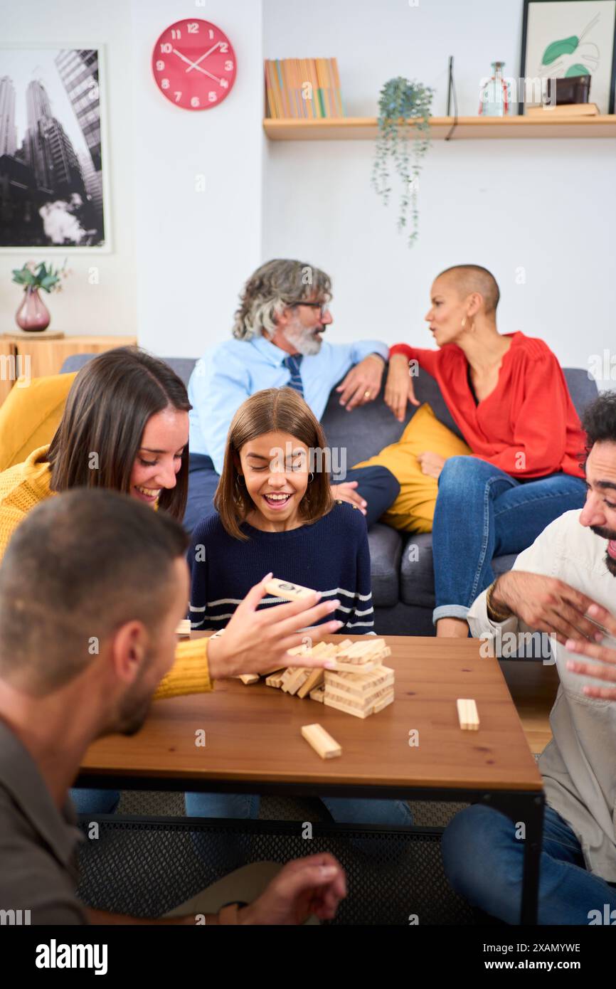 Excited multi-generational family gathering playing Jenga at home ...