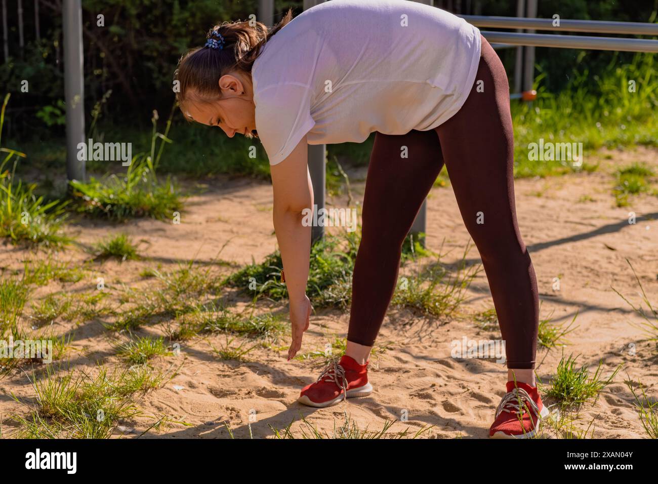 Woman performing a warm-up stretch routine in an outdoor setting. The ...
