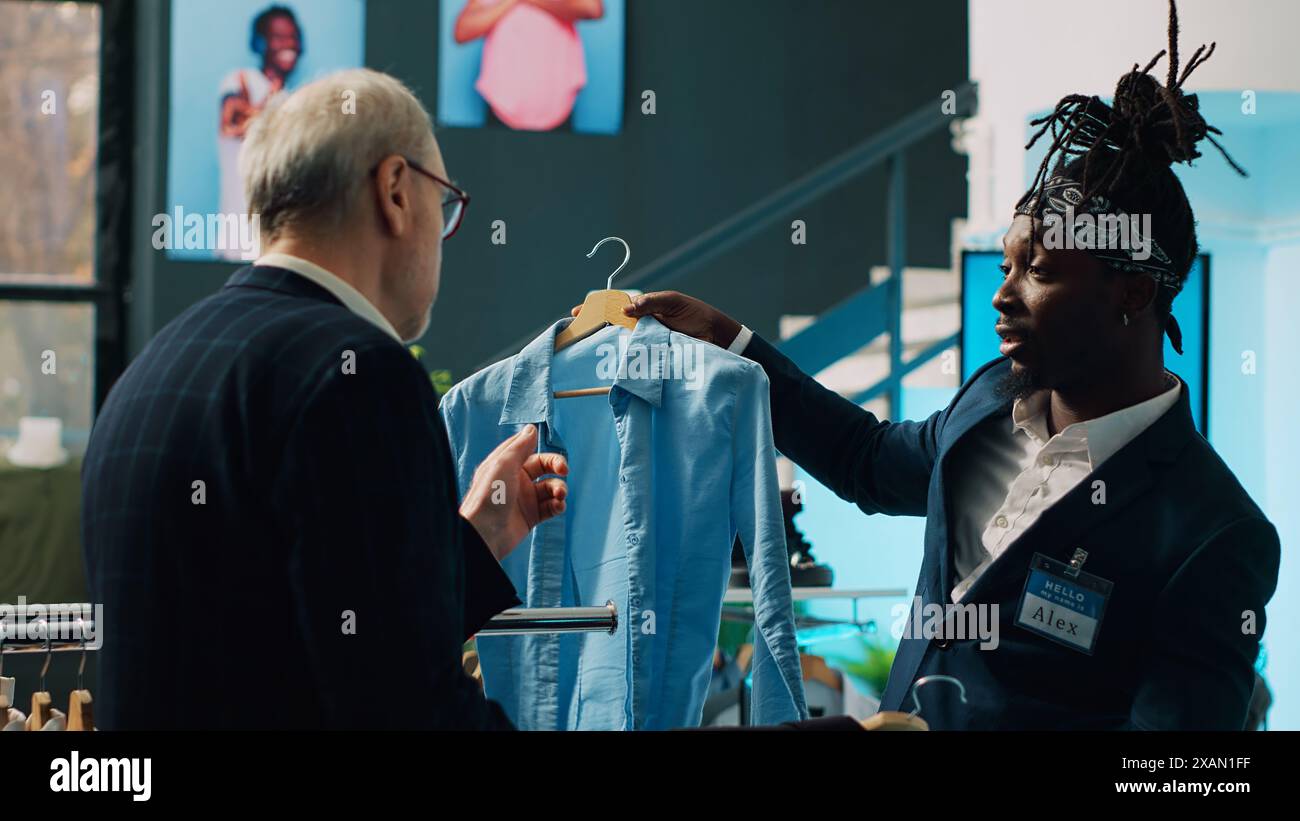 Retail assistant suggesting shirts for senior customer at shopping ...