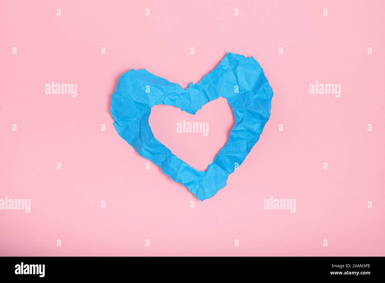 Blue crumpled paper texture in the shape of heart isolated on pink ...