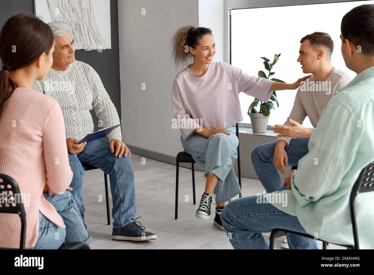 Mature woman calming sad man at group therapy session Stock Photo - Alamy