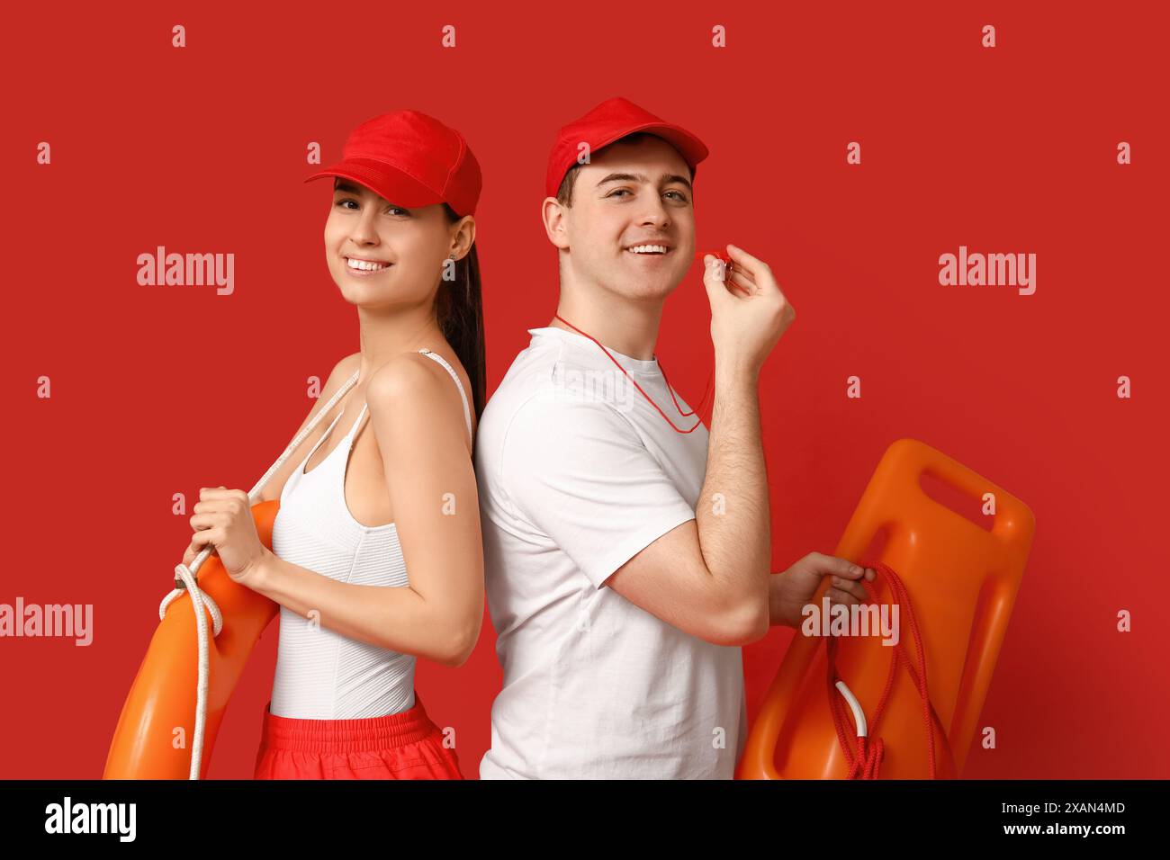 Lifeguards with ring buoy and rescue tube on red background Stock Photo ...