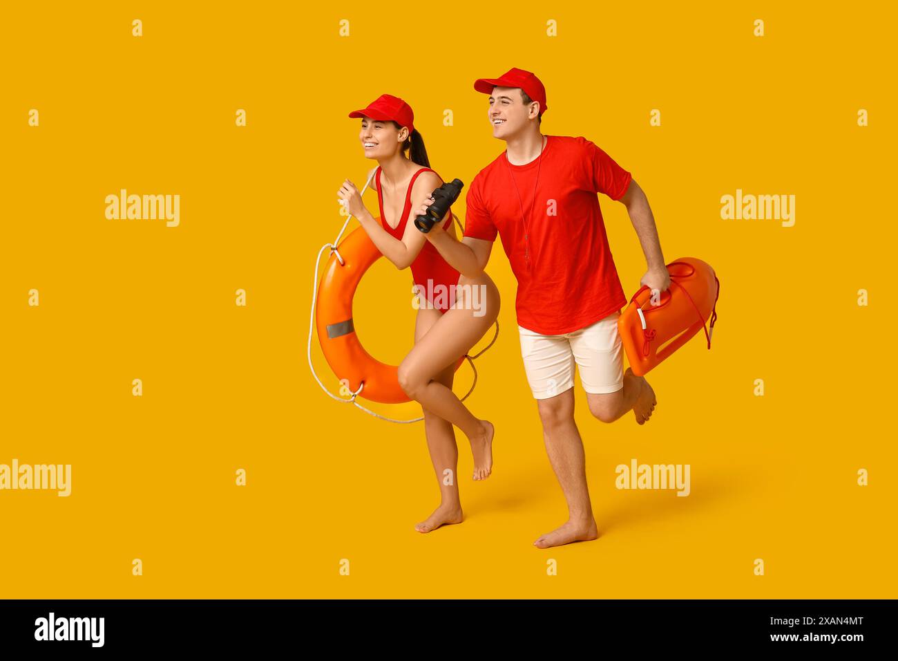 Lifeguards with ring buoy, rescue tube and binoculars running on yellow ...