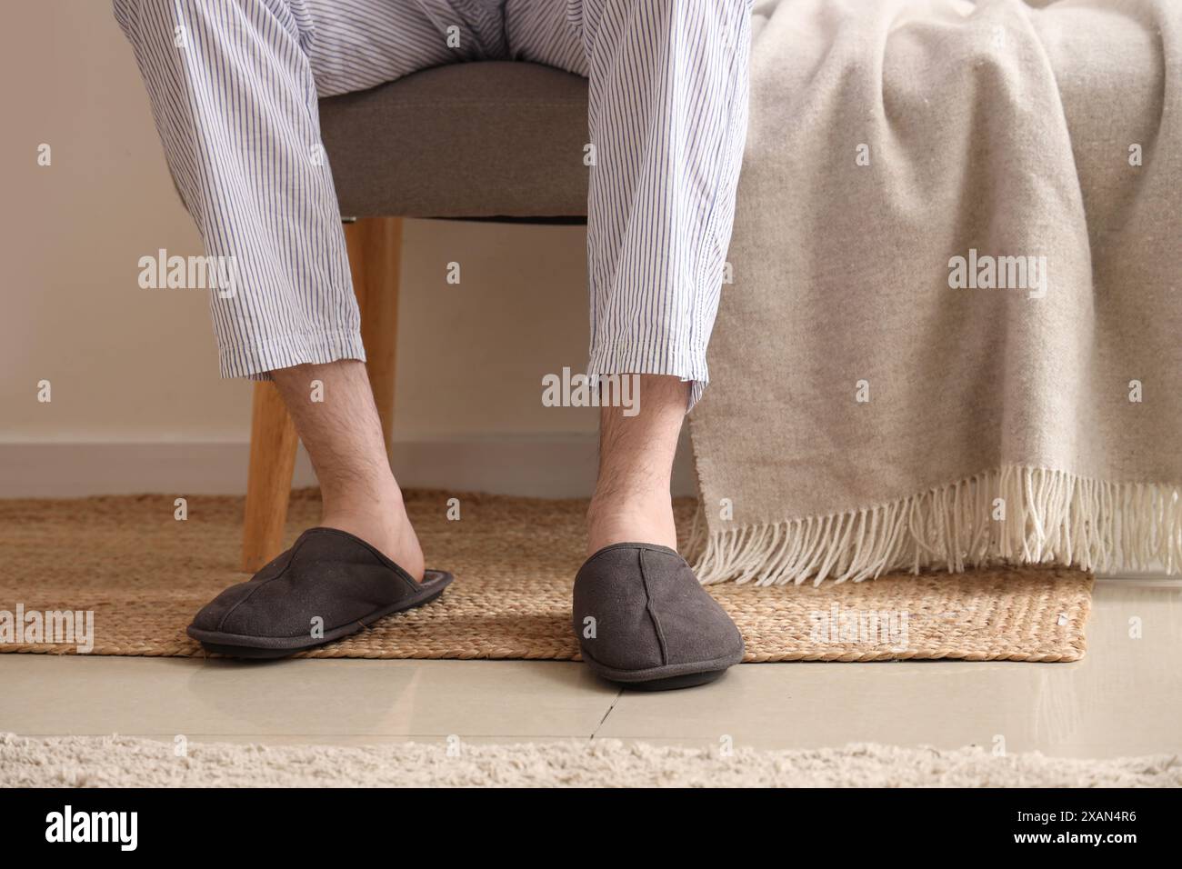 Man in slippers sitting on soft bench with plaid Stock Photo - Alamy