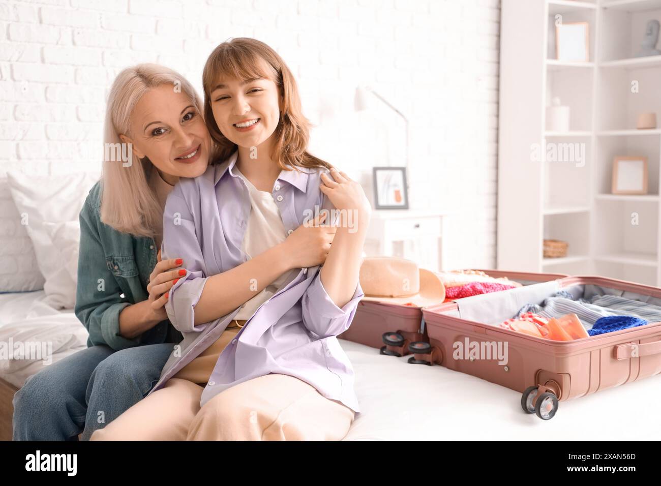 Mother hugging her daughter while packing suitcase in bedroom. Travel concept Stock Photo - Alamy