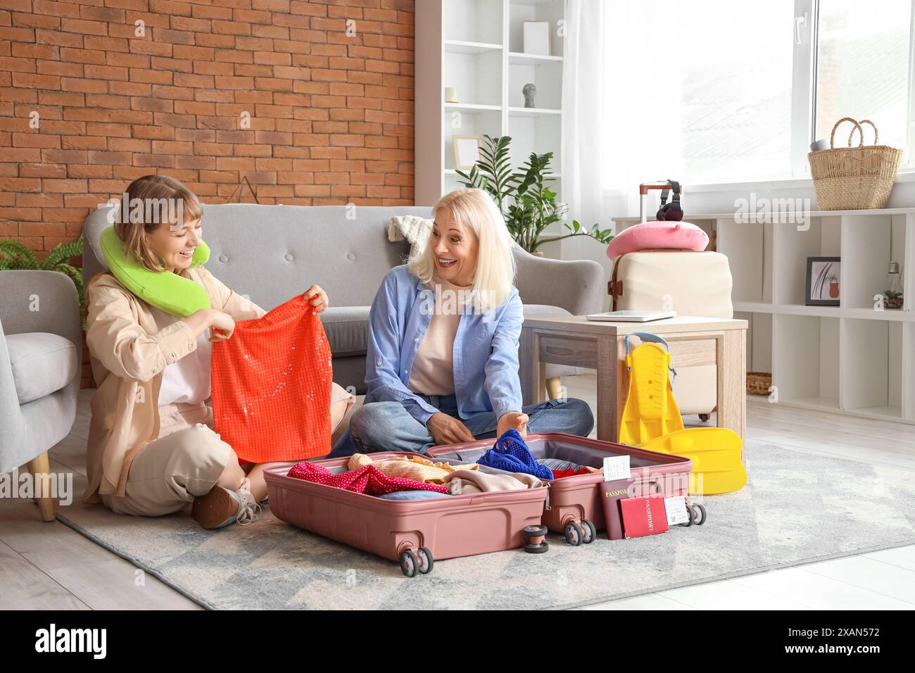 Mother and daughter packing their suitcase in living room. Travel ...