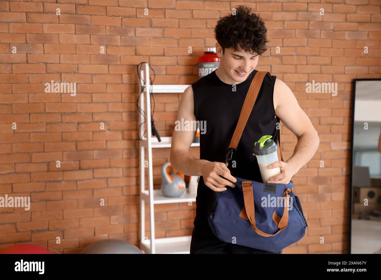 Sporty young man taking protein shake from bag in gym Stock Photo - Alamy