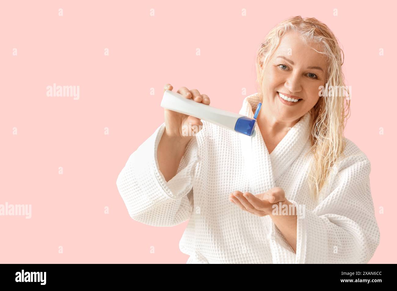 Mature woman pouring shampoo on pink background Stock Photo - Alamy
