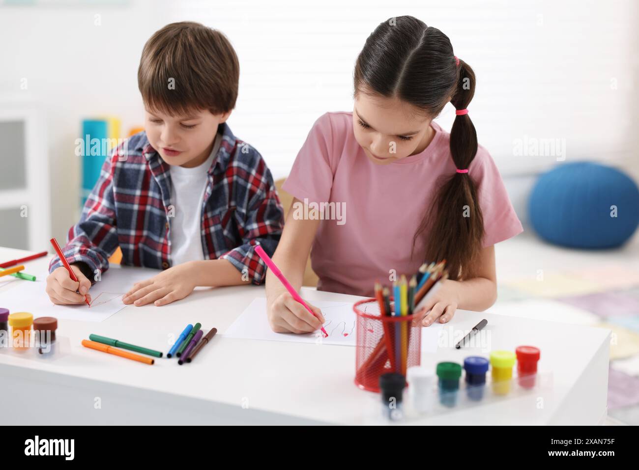 Happy brother and sister drawing at white table in room Stock Photo - Alamy
