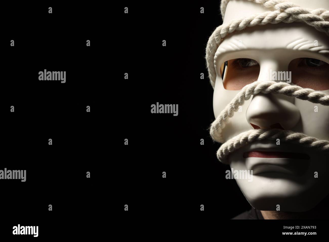 Theatrical performance. Man with plastic mask and hemp rope on black ...