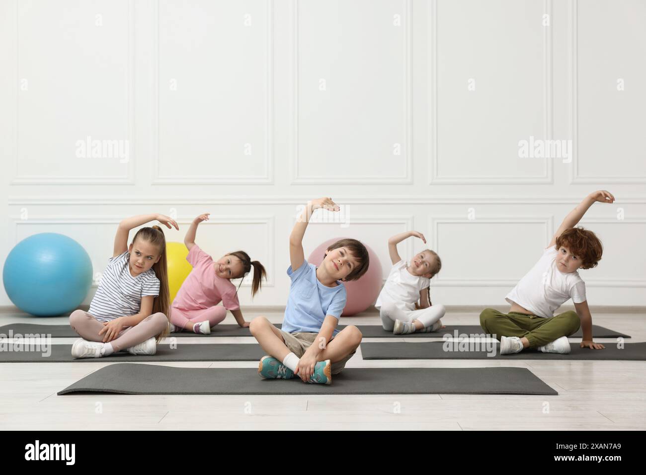 Group of children doing gymnastic exercises on mats indoors Stock Photo ...