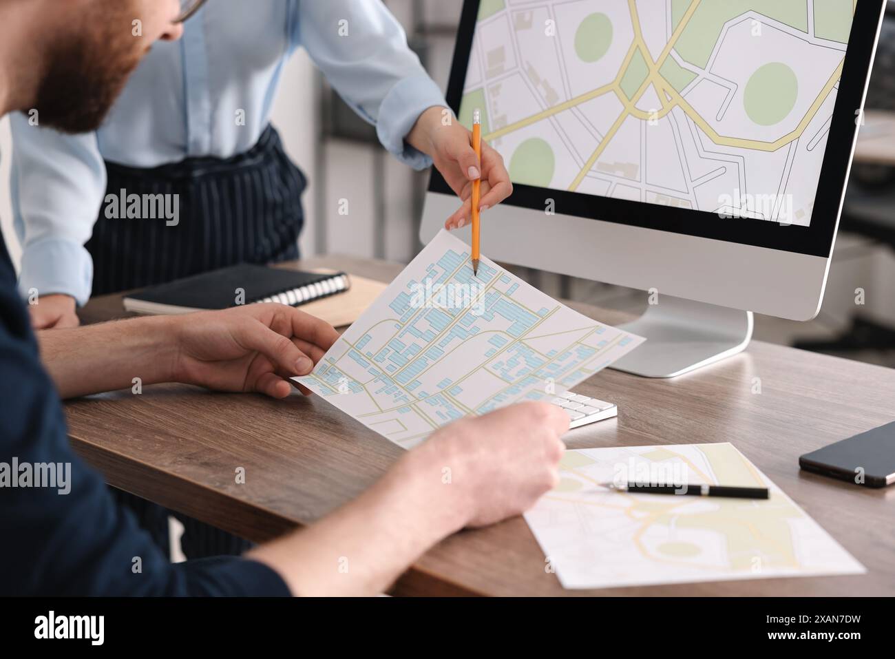Cartographers working with cadastral maps at wooden table in office ...