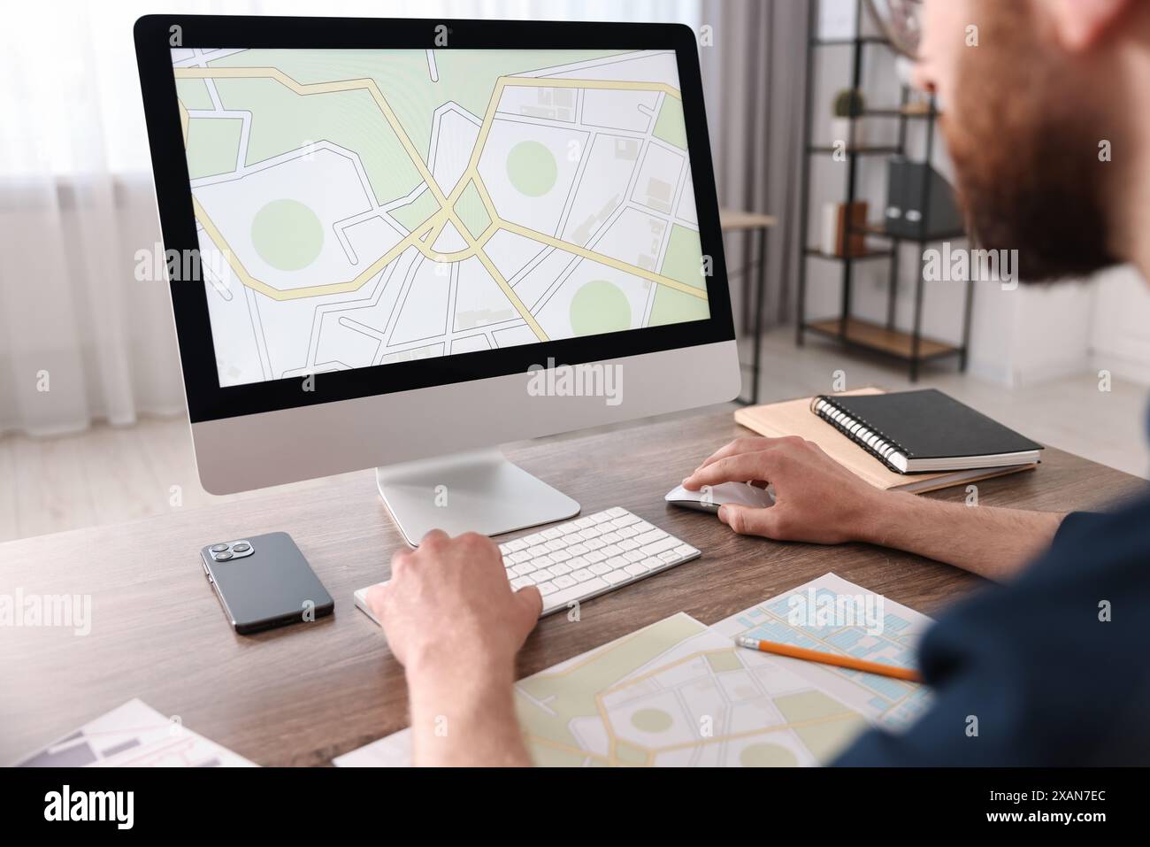 Cartographer working with cadastral map on computer at wooden table in ...