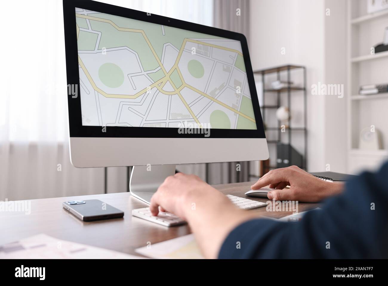 Cartographer working with cadastral map on computer at wooden table in ...