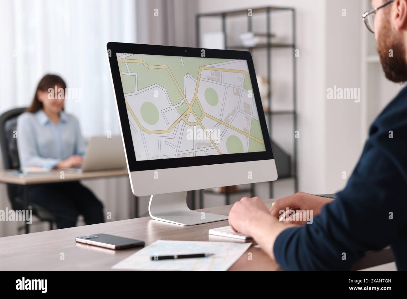 Cartographer working with cadastral map on computer at wooden table in ...