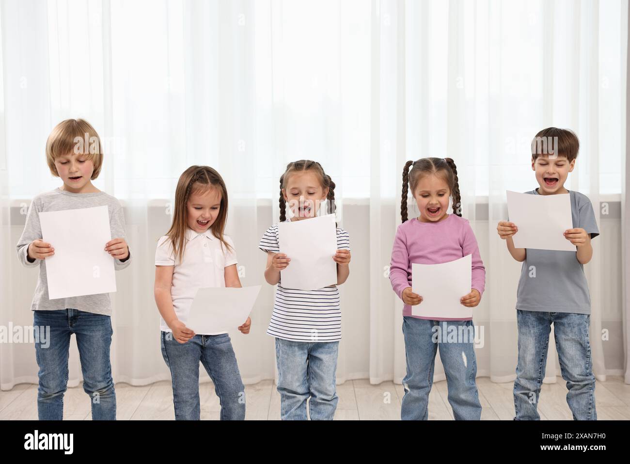 Group of children with sheets of paper singing indoors Stock Photo - Alamy