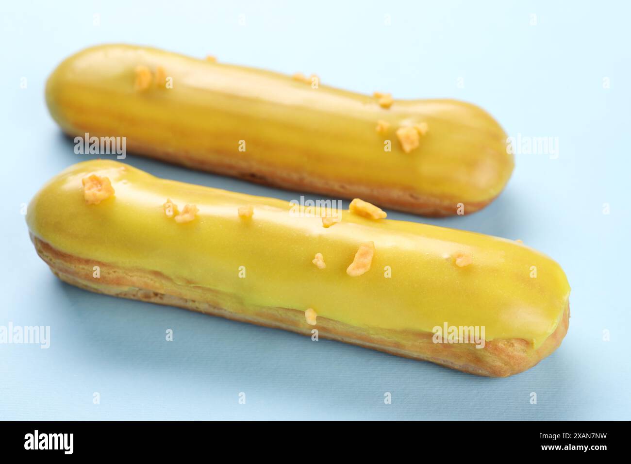 Delicious eclairs covered with glaze on light blue background Stock ...