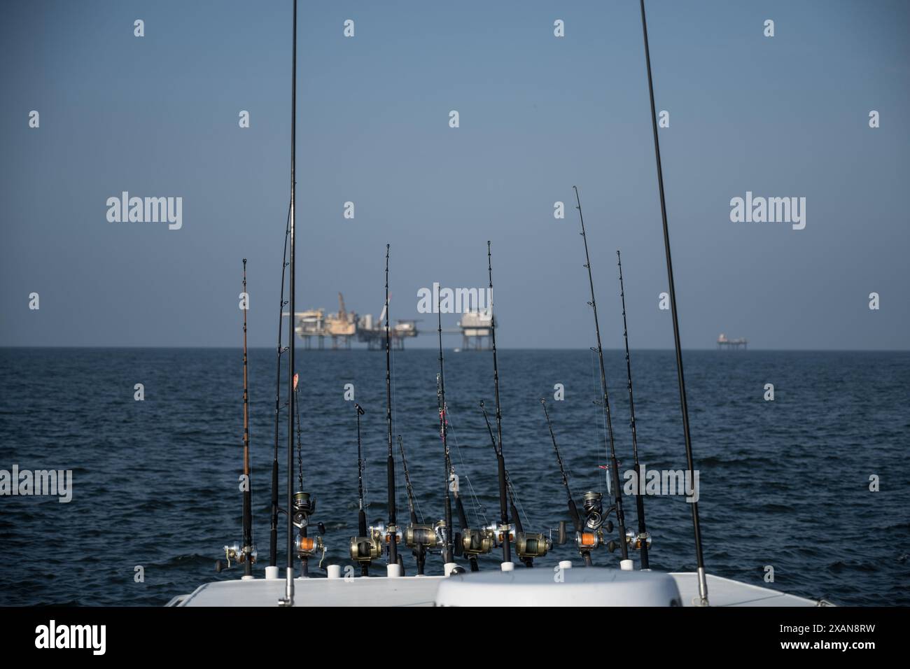 Anglers aboard a fishing boat target tuna near a large floating oil ...