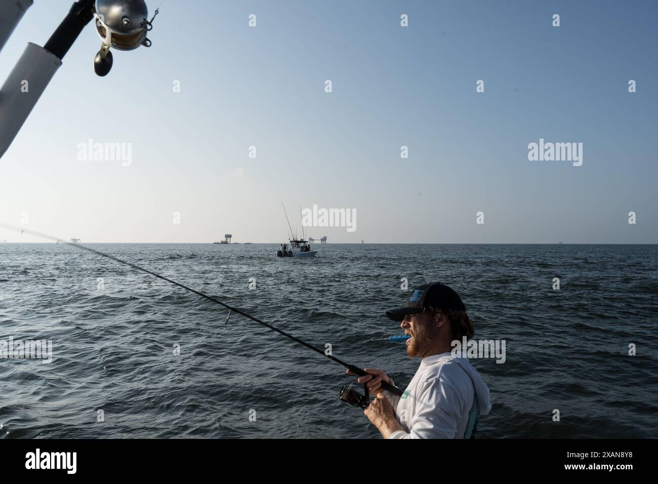 An angler fishes for baitfish while surrounded by offshore oil ...