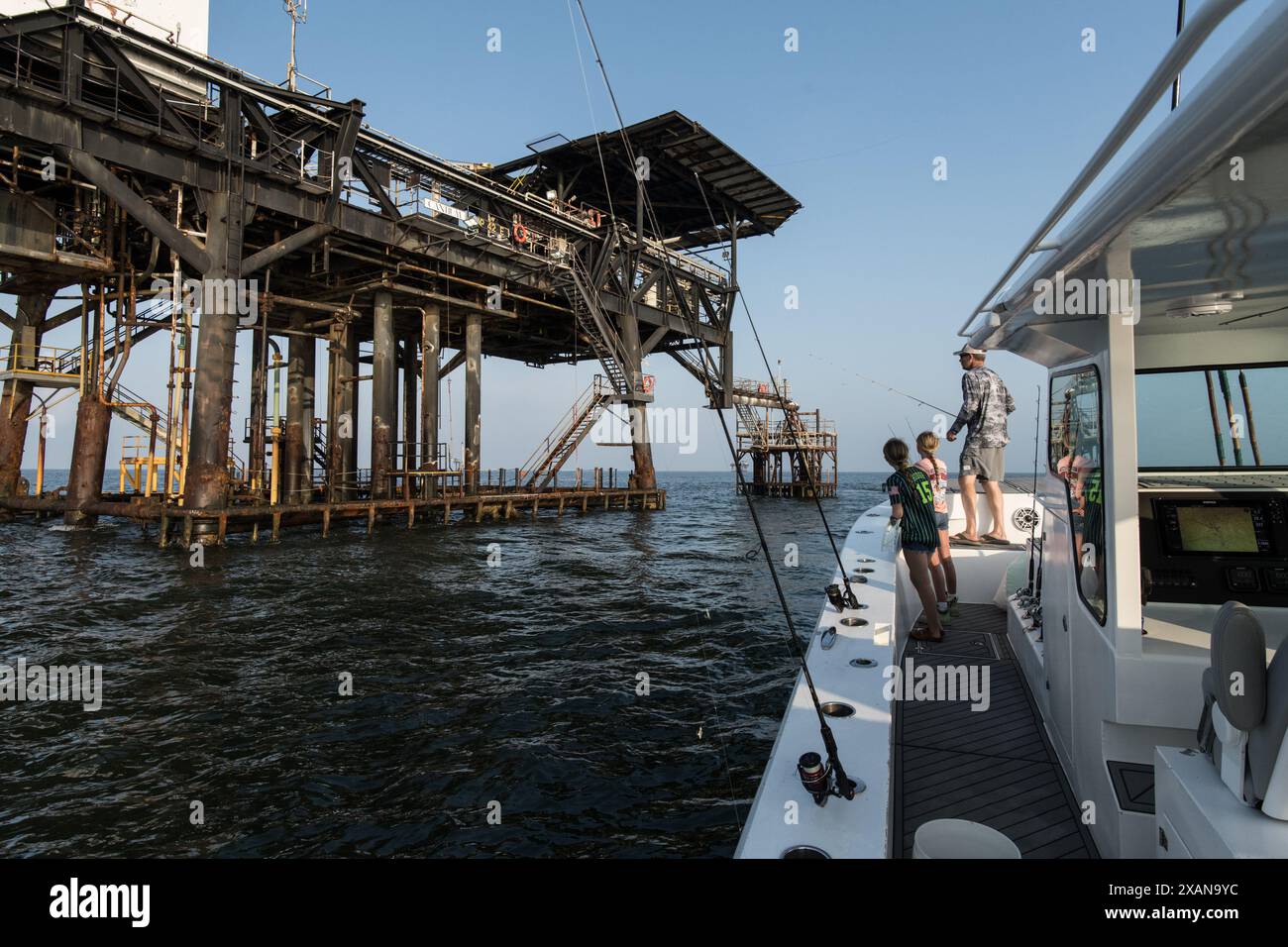 Anglers fish for baitfish while surrounded by offshore oil platforms in ...