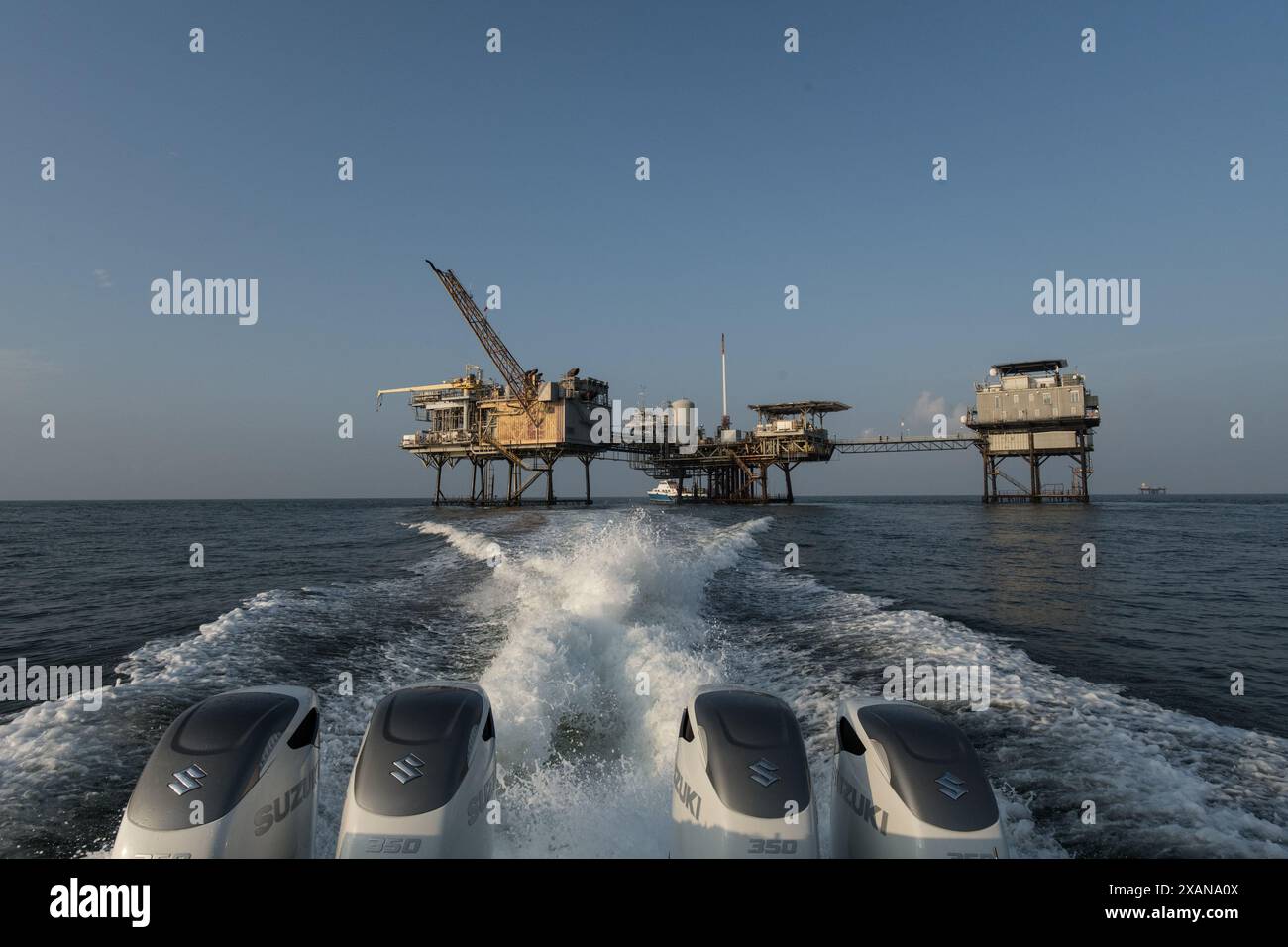 Anglers aboard a fishing boat near offshore oil rigs in the Gulf of ...