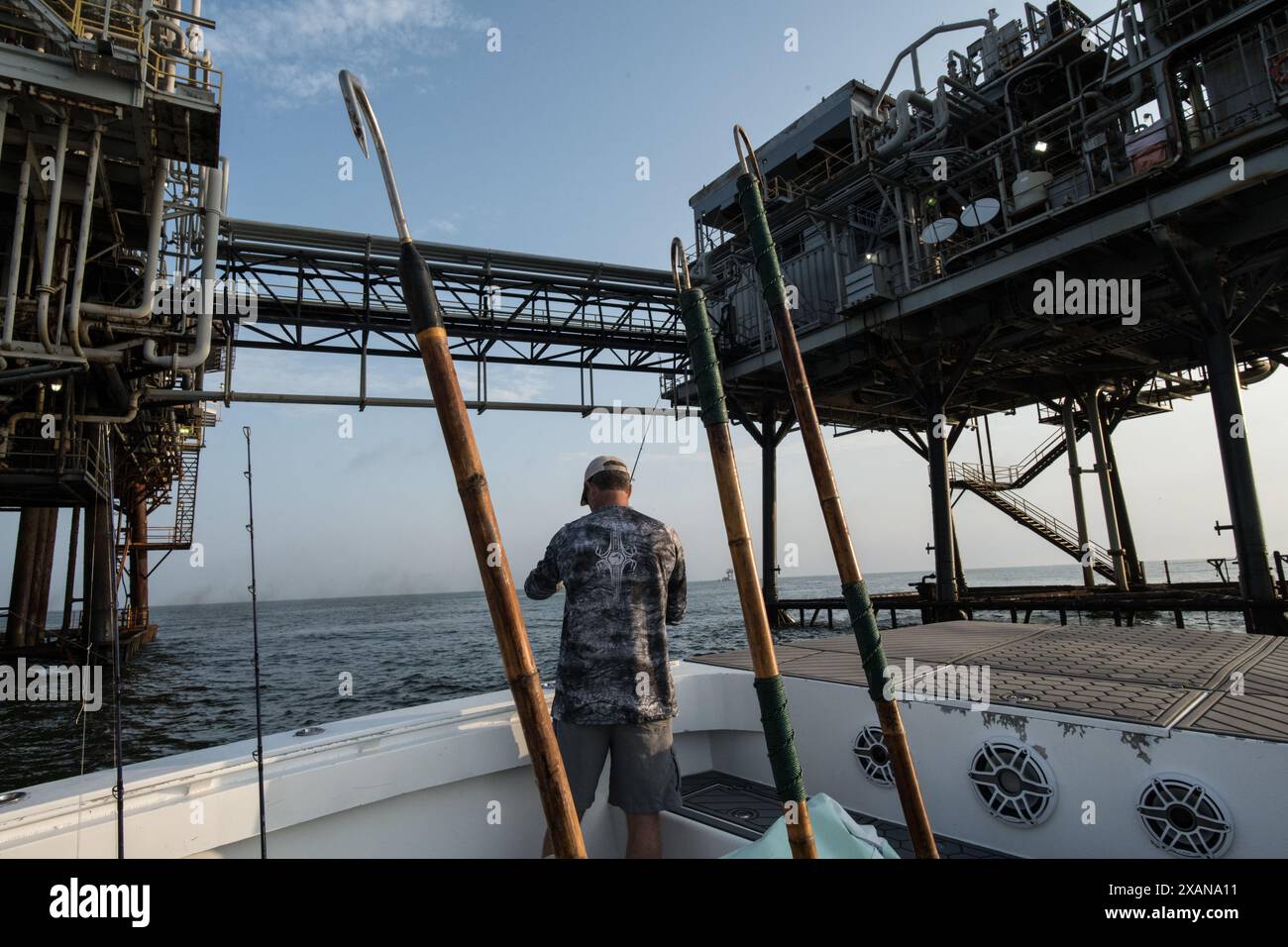 An angler fishes for baitfish while surrounded by offshore oil ...