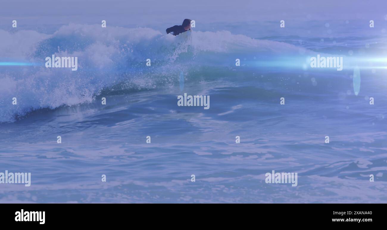 Image of lights over caucasian male surfboarding on waves Stock Photo ...