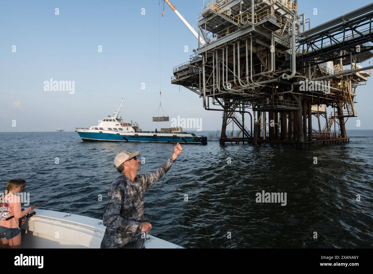 An angler fishes for baitfish while surrounded by offshore oil ...