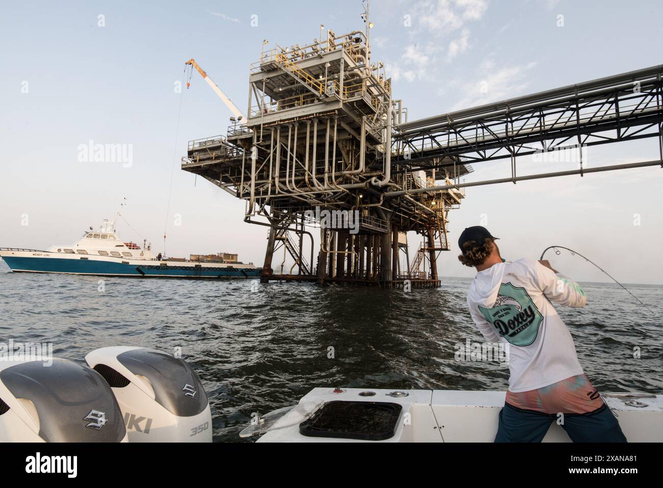 An angler fishes for baitfish while surrounded by offshore oil ...