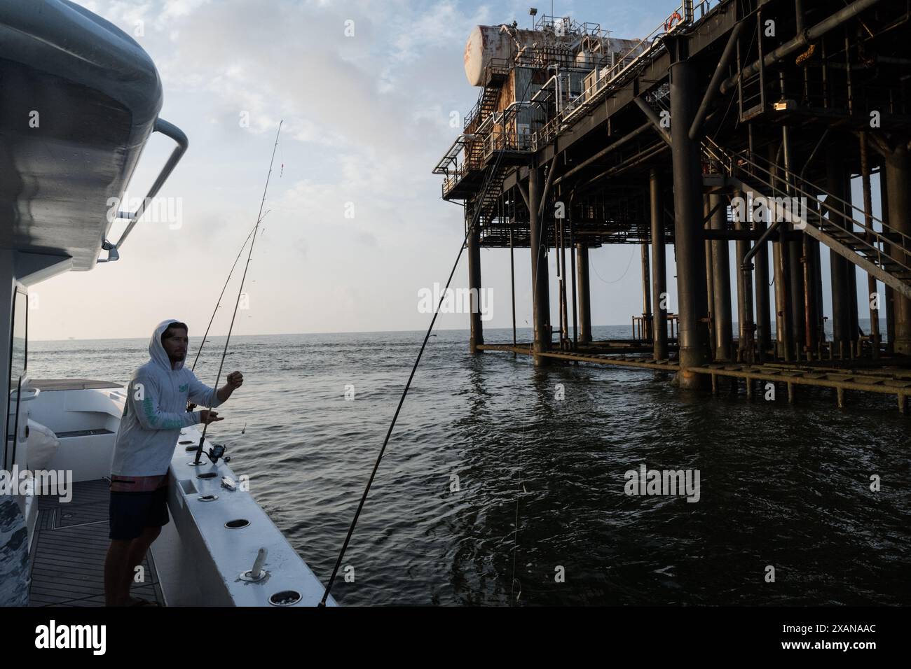 An angler fishes for baitfish while surrounded by offshore oil ...