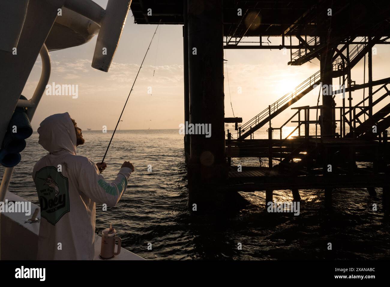 An angler fishes for baitfish while surrounded by offshore oil ...