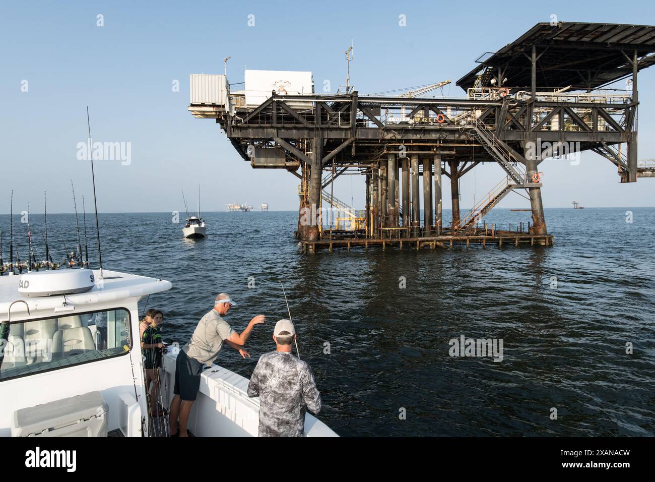 Anglers fish for baitfish while surrounded by offshore oil platforms in ...