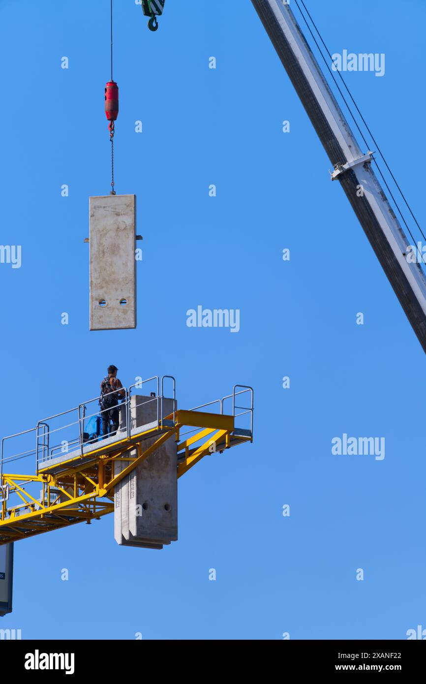 Construction worker guides a concrete slab block into position on a new ...