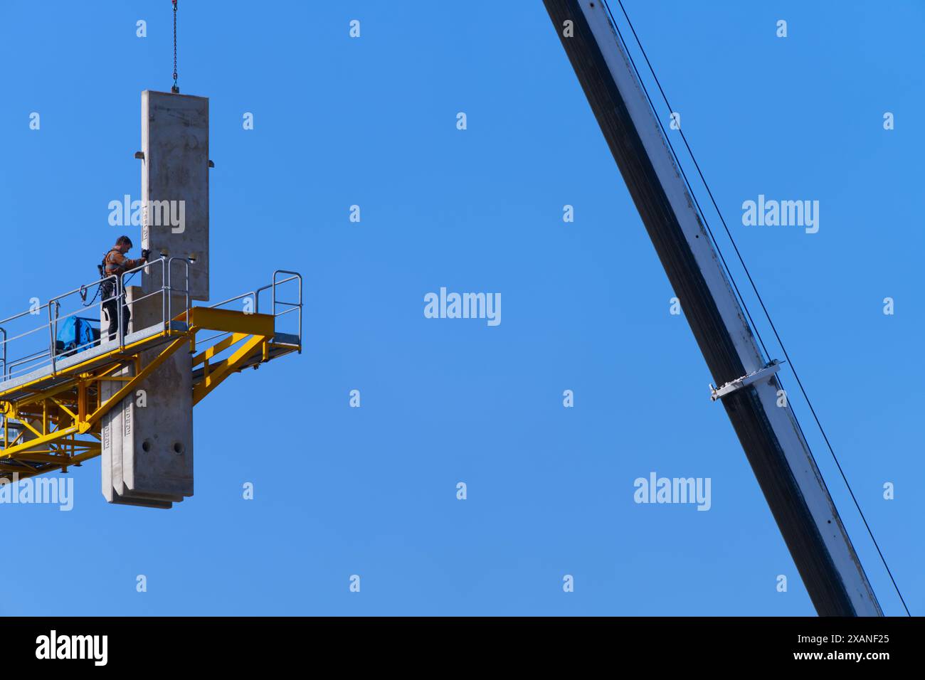 Construction worker guides a concrete slab block into position on a new ...
