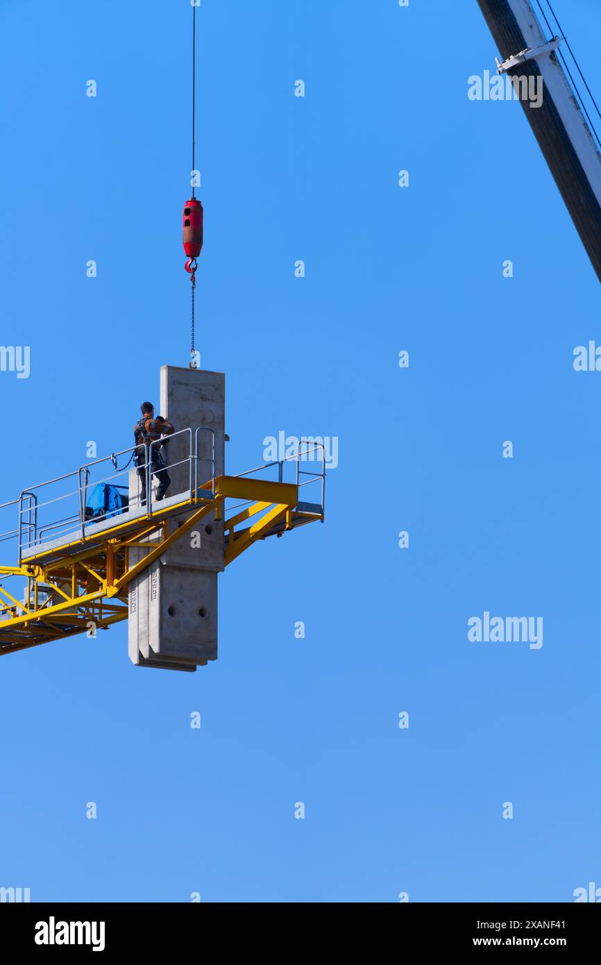 Construction worker guides a concrete slab block into position on a new ...