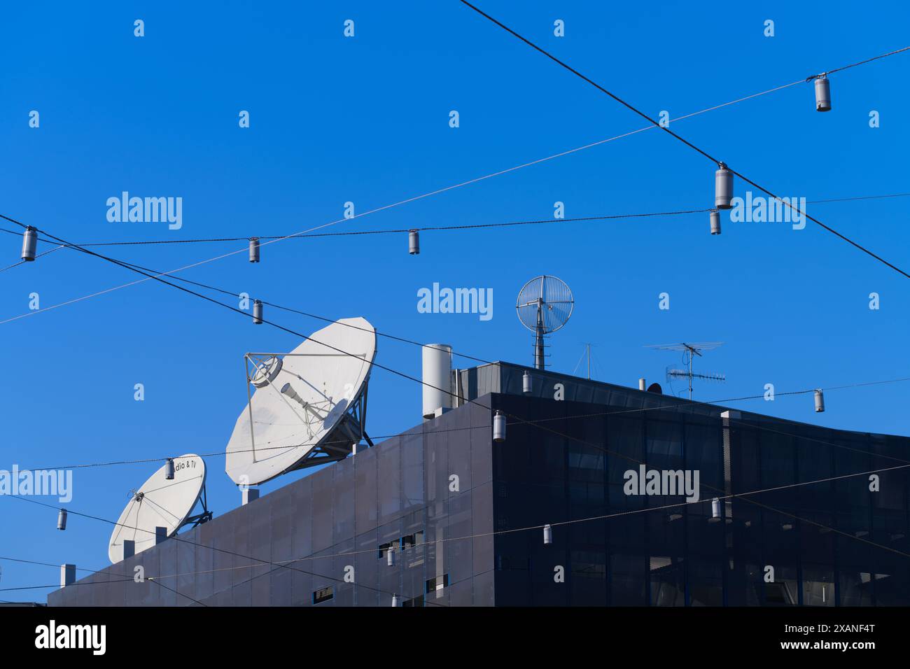 Circular satellite dish sit on the roof of a symmetrical building, with ...