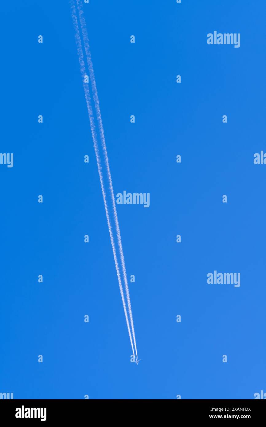 Blue sky contrails from a jet airliner flying at high altitude, central ...