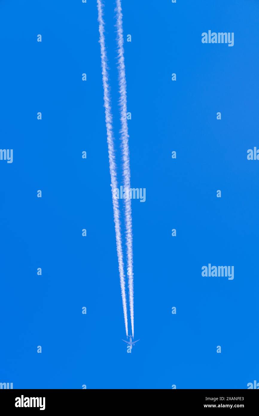 Blue sky contrails from a jet airliner flying at high altitude, central ...
