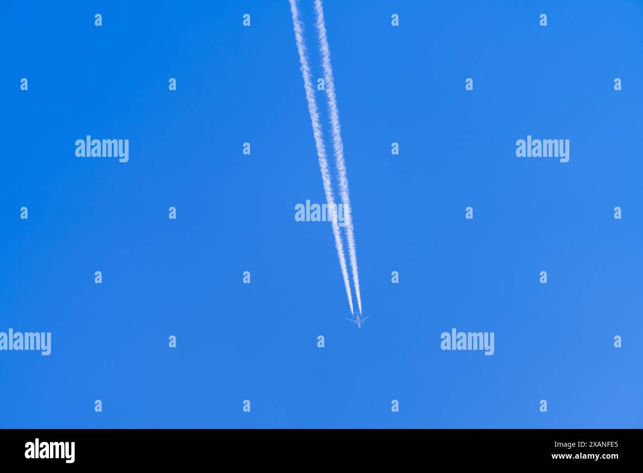 Blue sky contrails from a jet airliner flying at high altitude, central ...