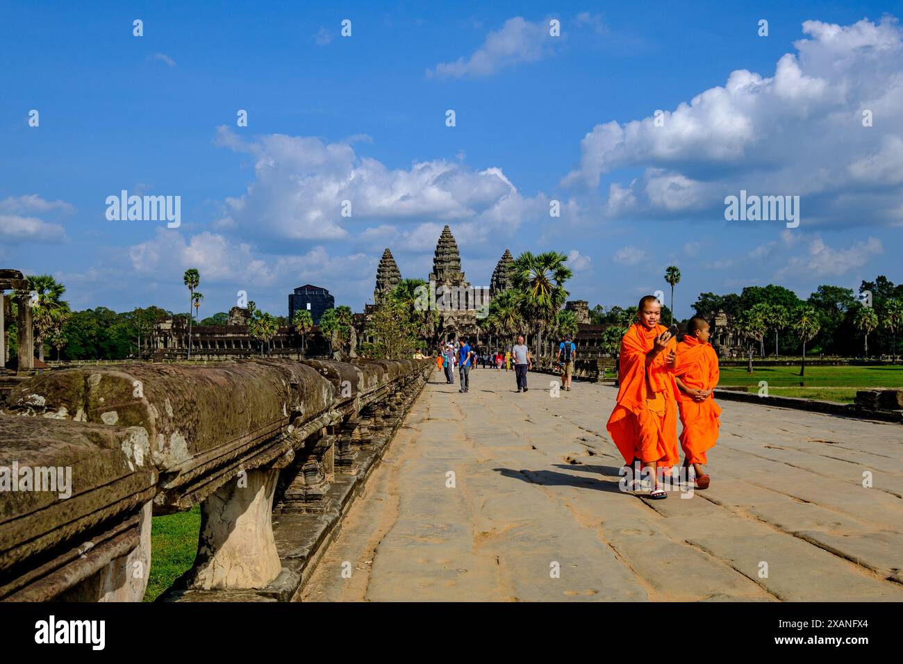 Monks in orange robes walking at Angkor Wat, Cambodia, under a vibrant ...
