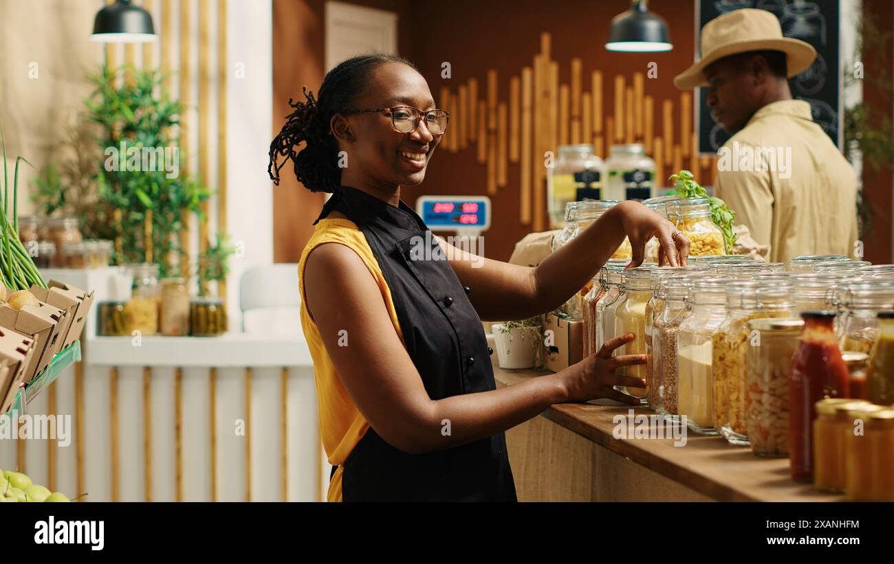 Local merchant organizing homemade pasta in reusable jars at zero waste ...