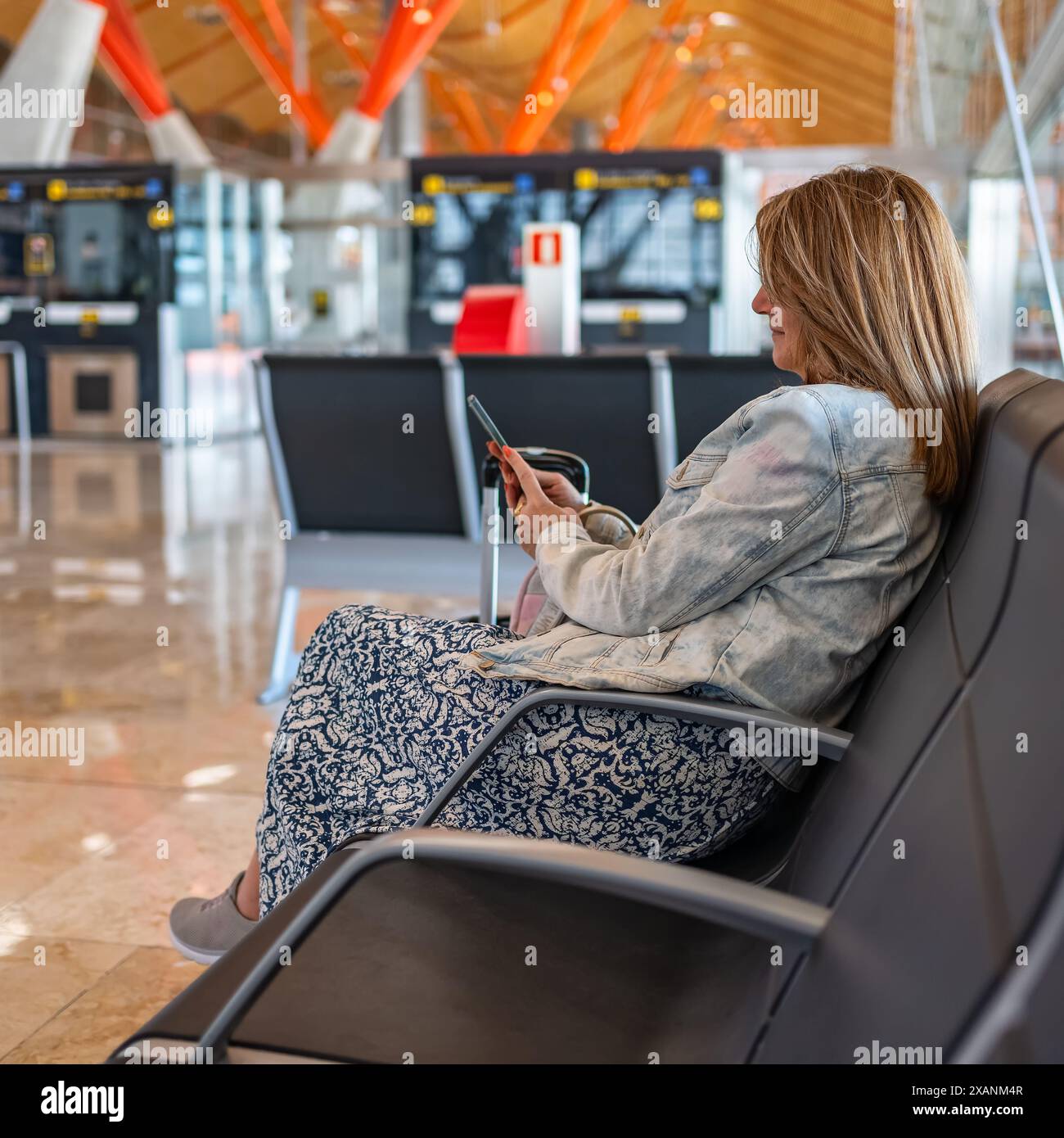 Woman sits in the airport terminal while waiting to board the plane ...