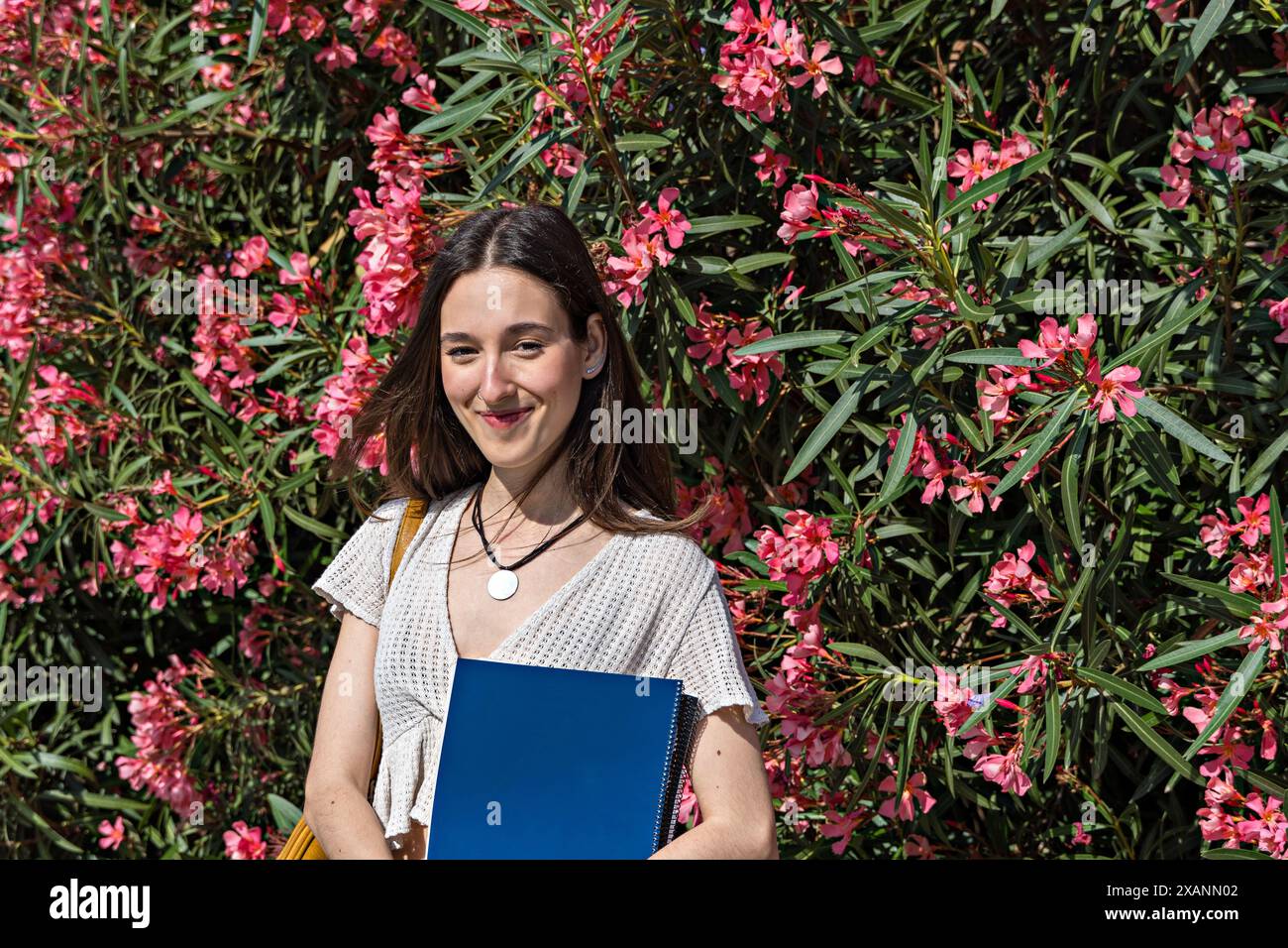 Smiling young college girl with backpack and books, posing in front of ...